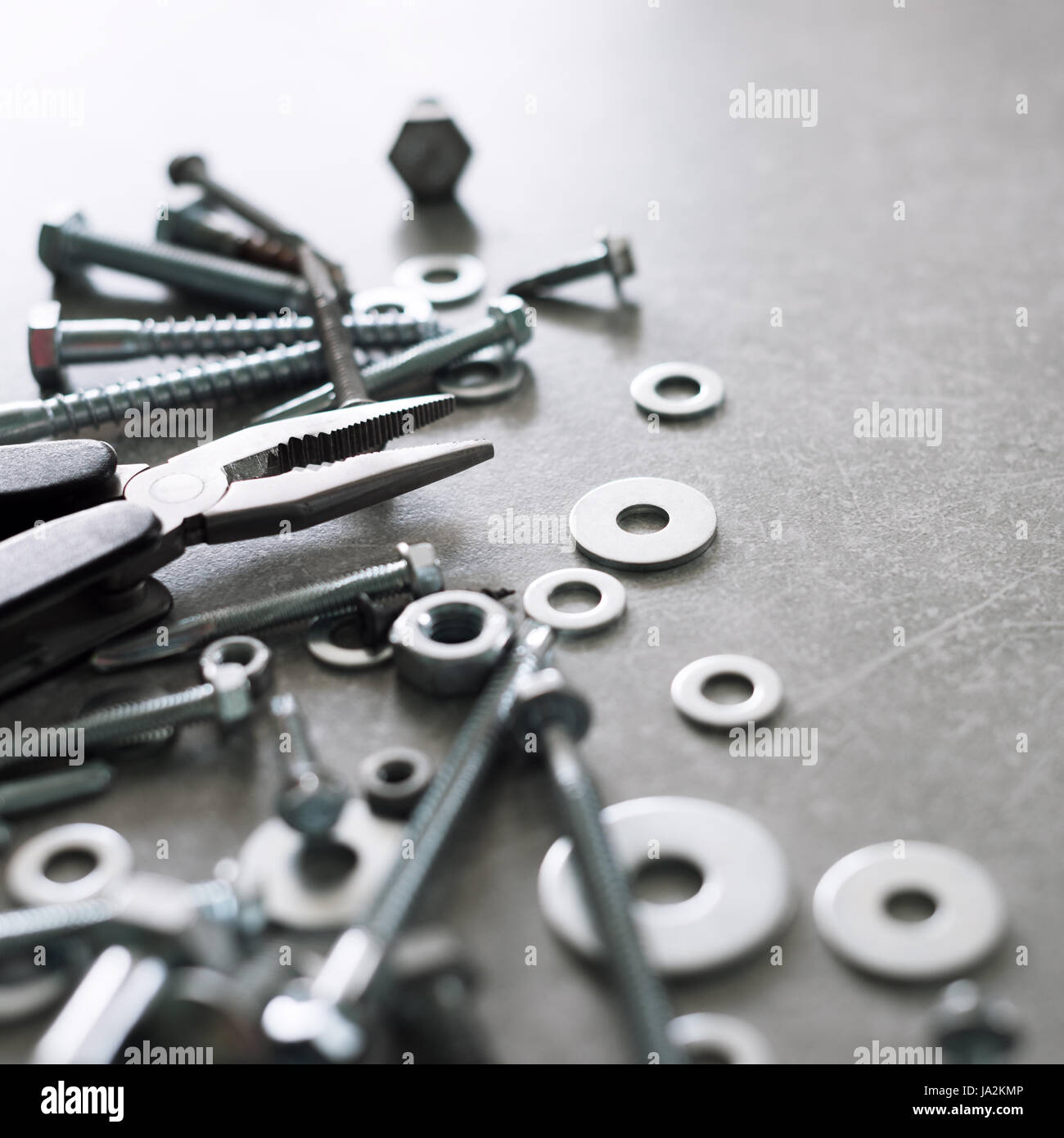 Construction tools. The screws, nuts and bolts with pliers on concrete ...