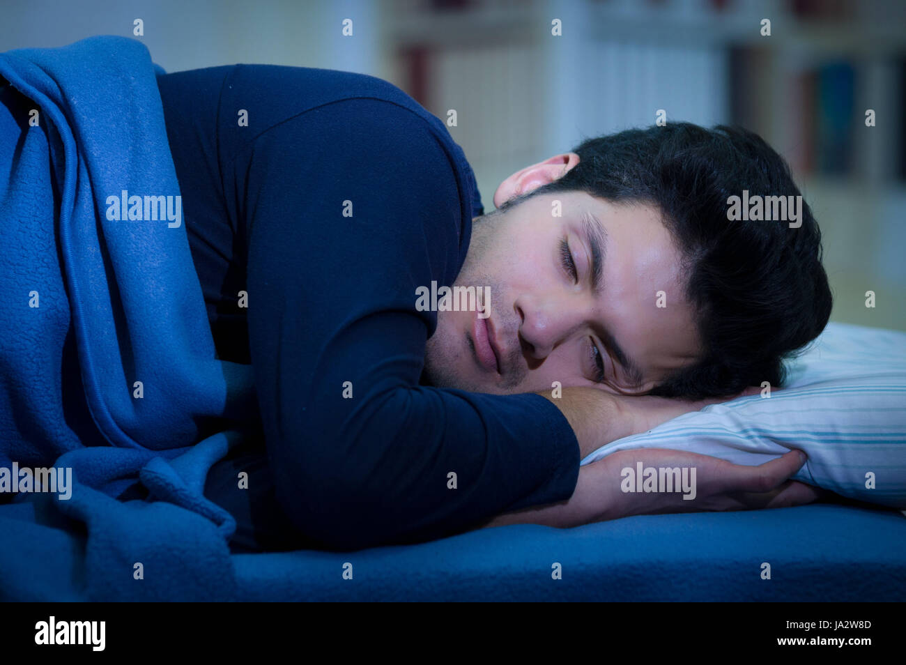 Handsome young man in bed falling asleep after suffering insomnia and ...