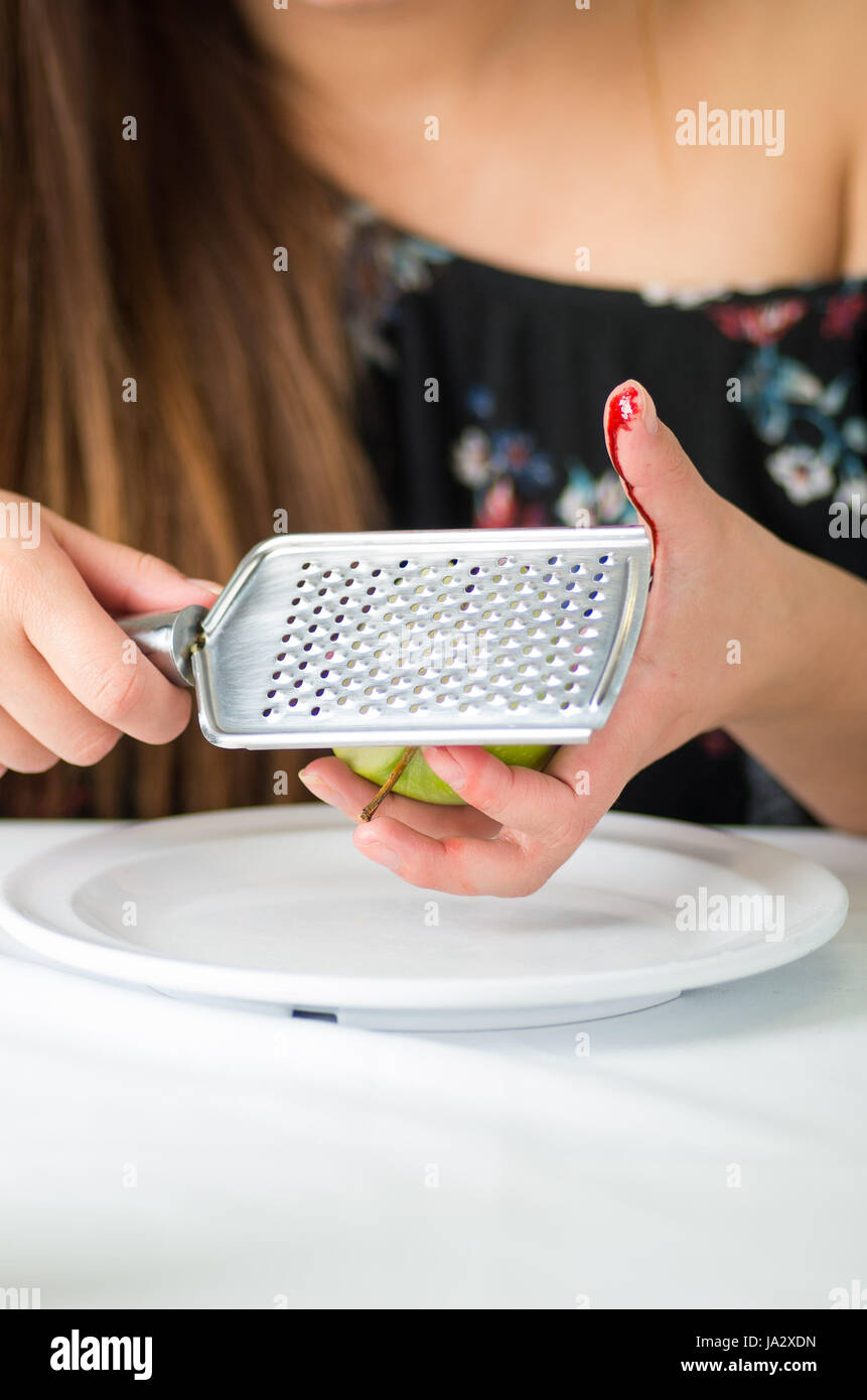 Close up of a woman's hand injured her finger using a grating in plate ...