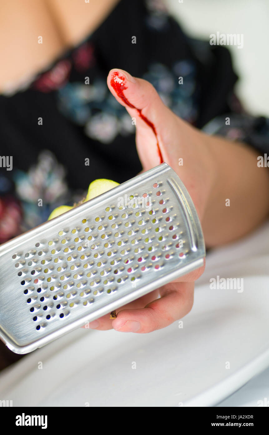 Close up of a woman's hand injured her finger using a grating in plate ...