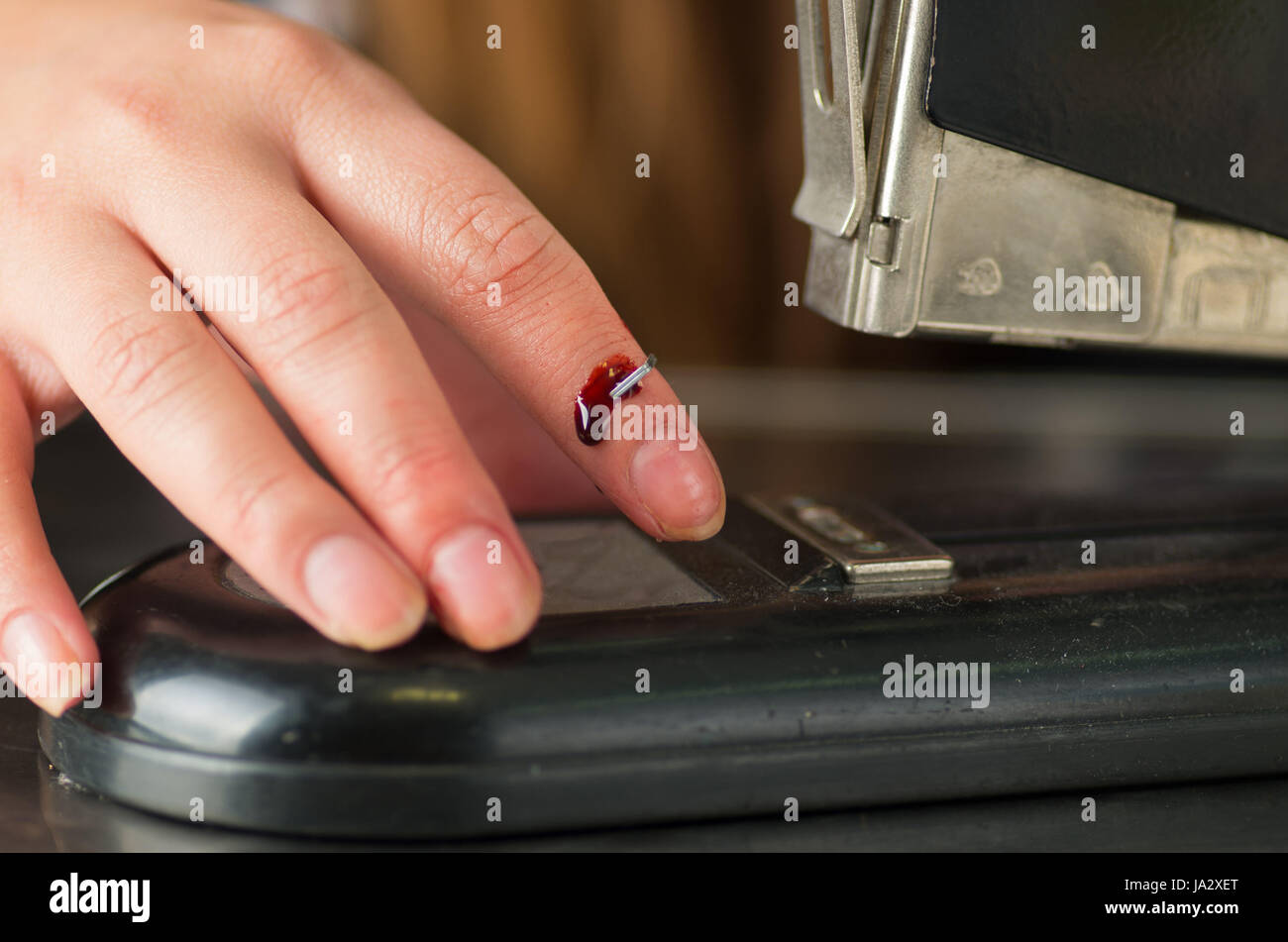Close up of a youn woman injured her finger using a stapler, bleeding ...