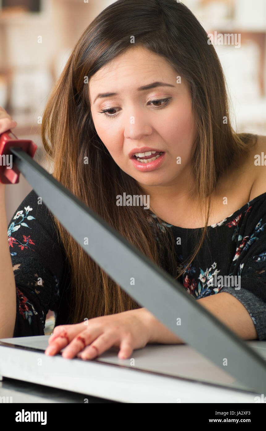 Young beautiful woman using a paper cutter, had an accident and cut her ...