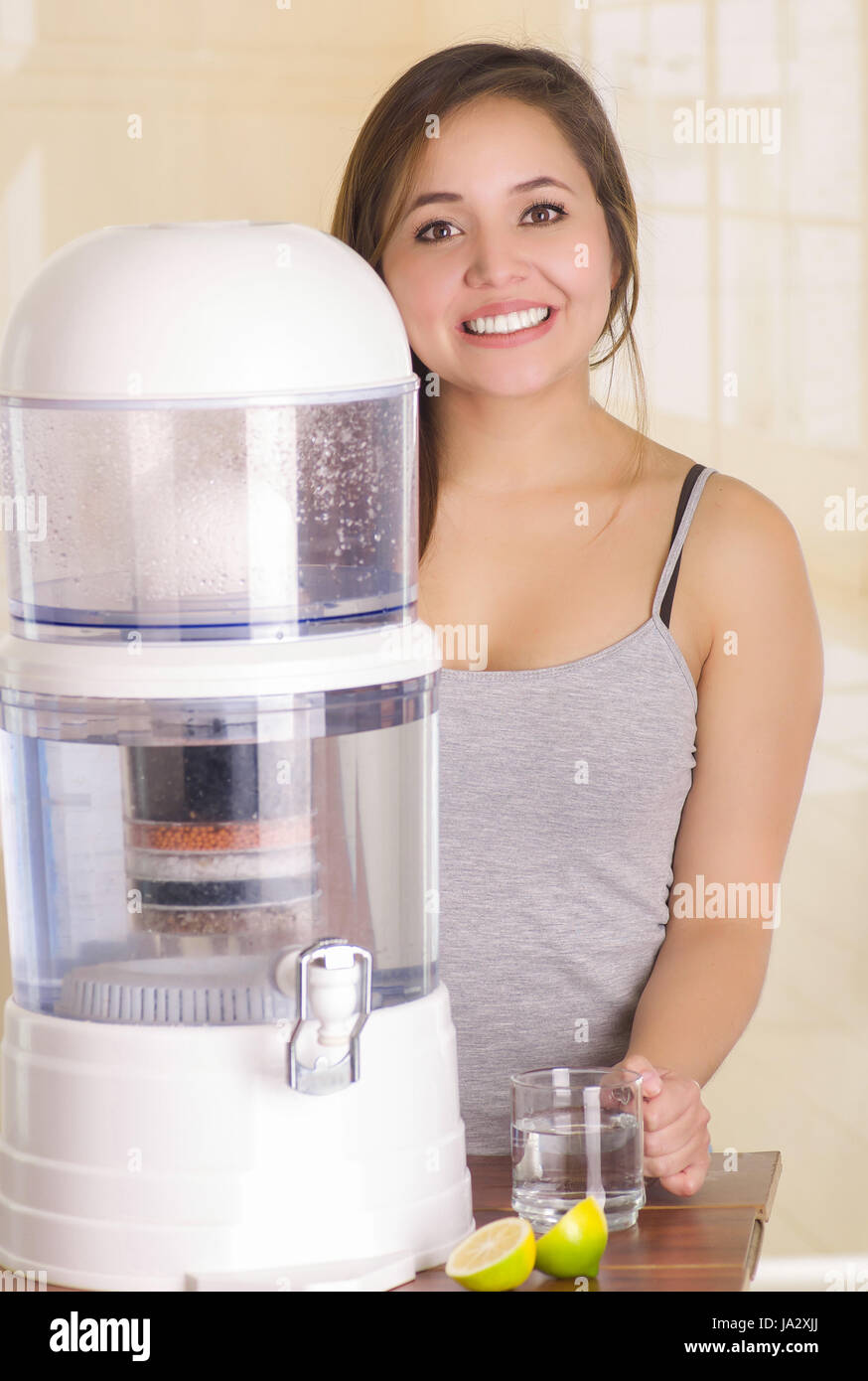 Beautiful girl behind a filter system of water purifier on a kitchen ...