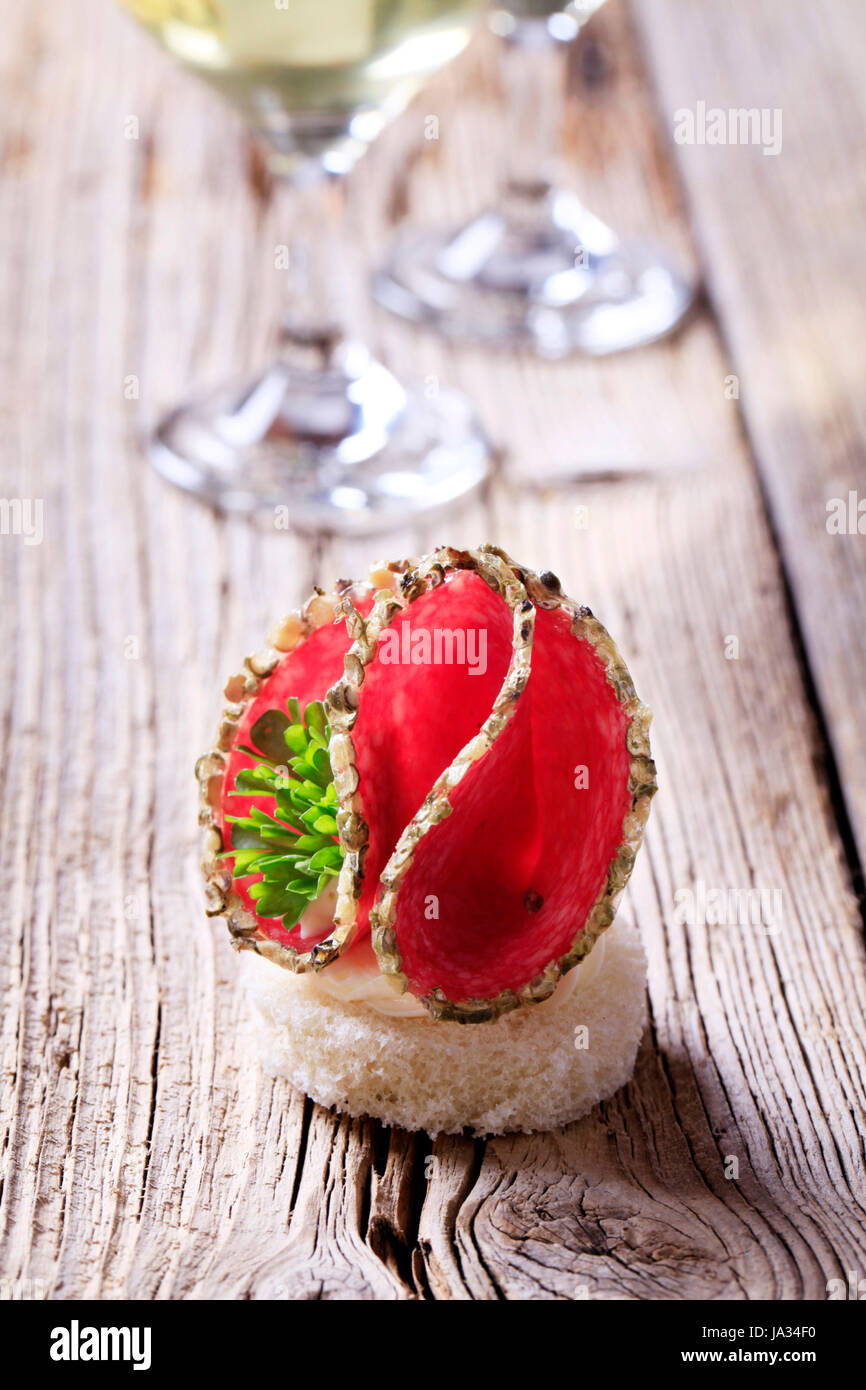 Bite-sized appetizer - Slice of salami on bread Stock Photo - Alamy