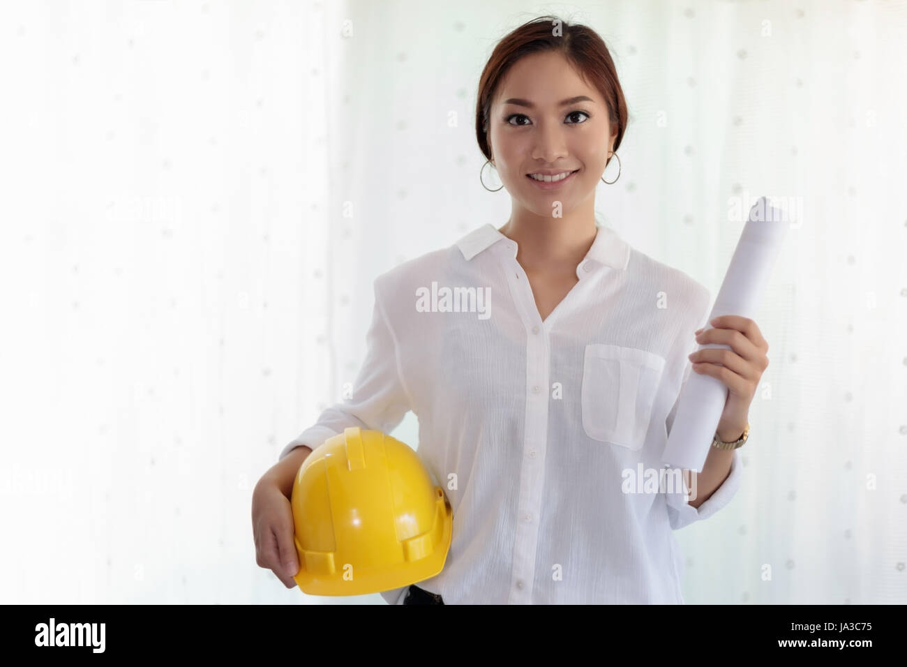 Asian women engineering holding blueprints , hard hat for working at ...
