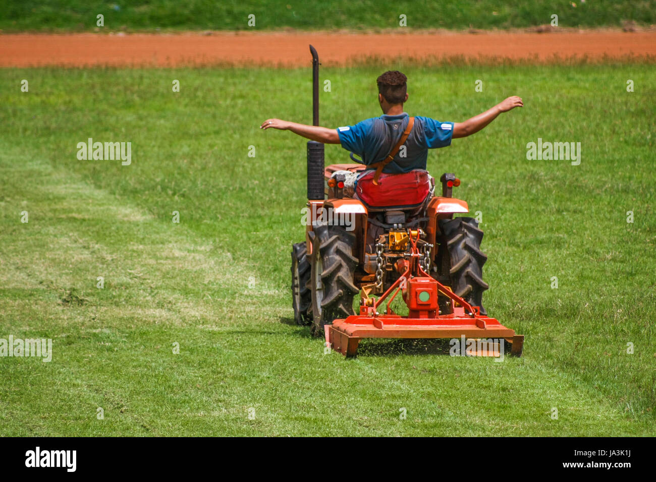 a man on mower cutting grass in football field Stock Photo - Alamy
