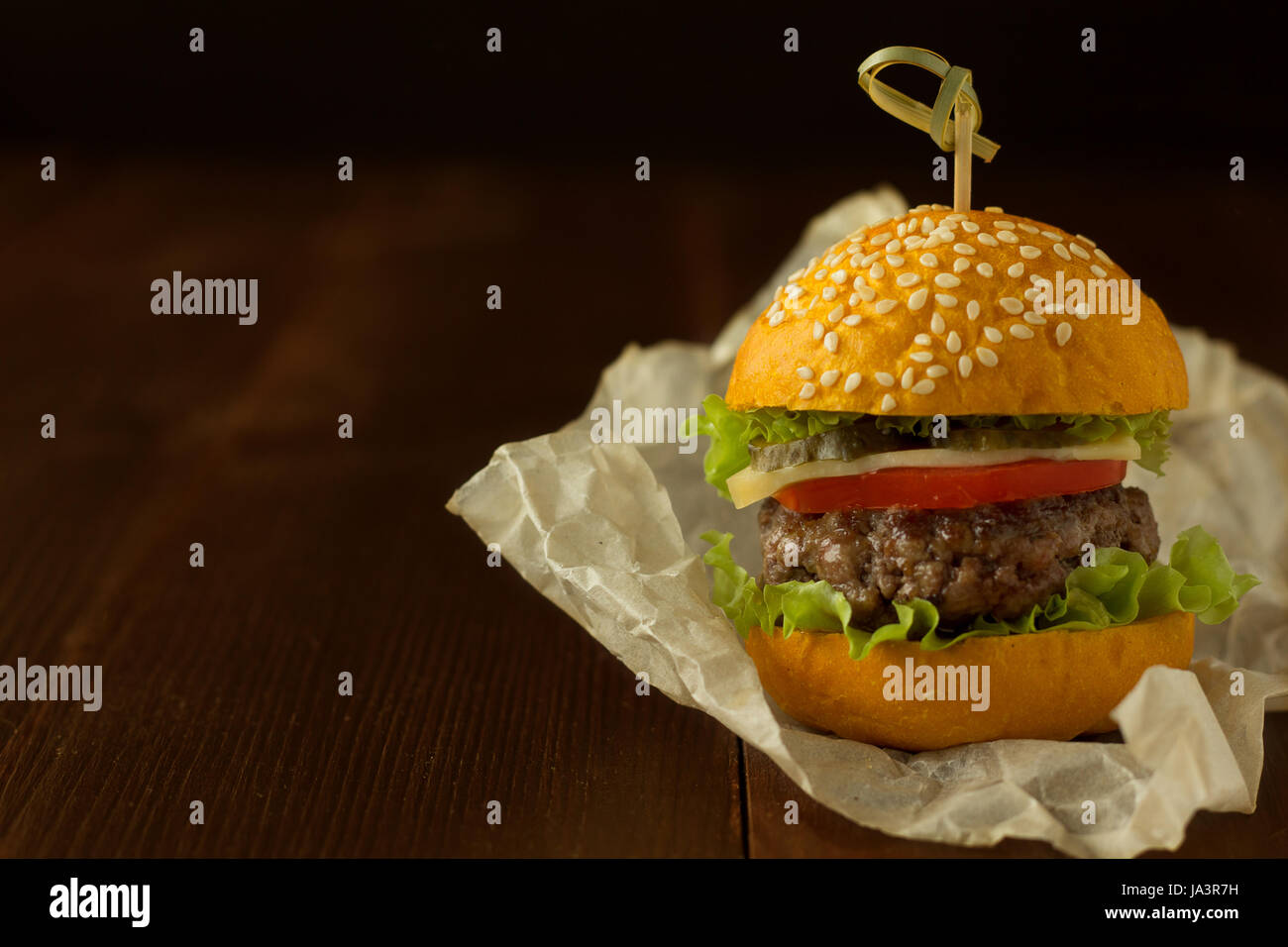 Burger in yellow bun on wooden table selective focus Stock Photo - Alamy