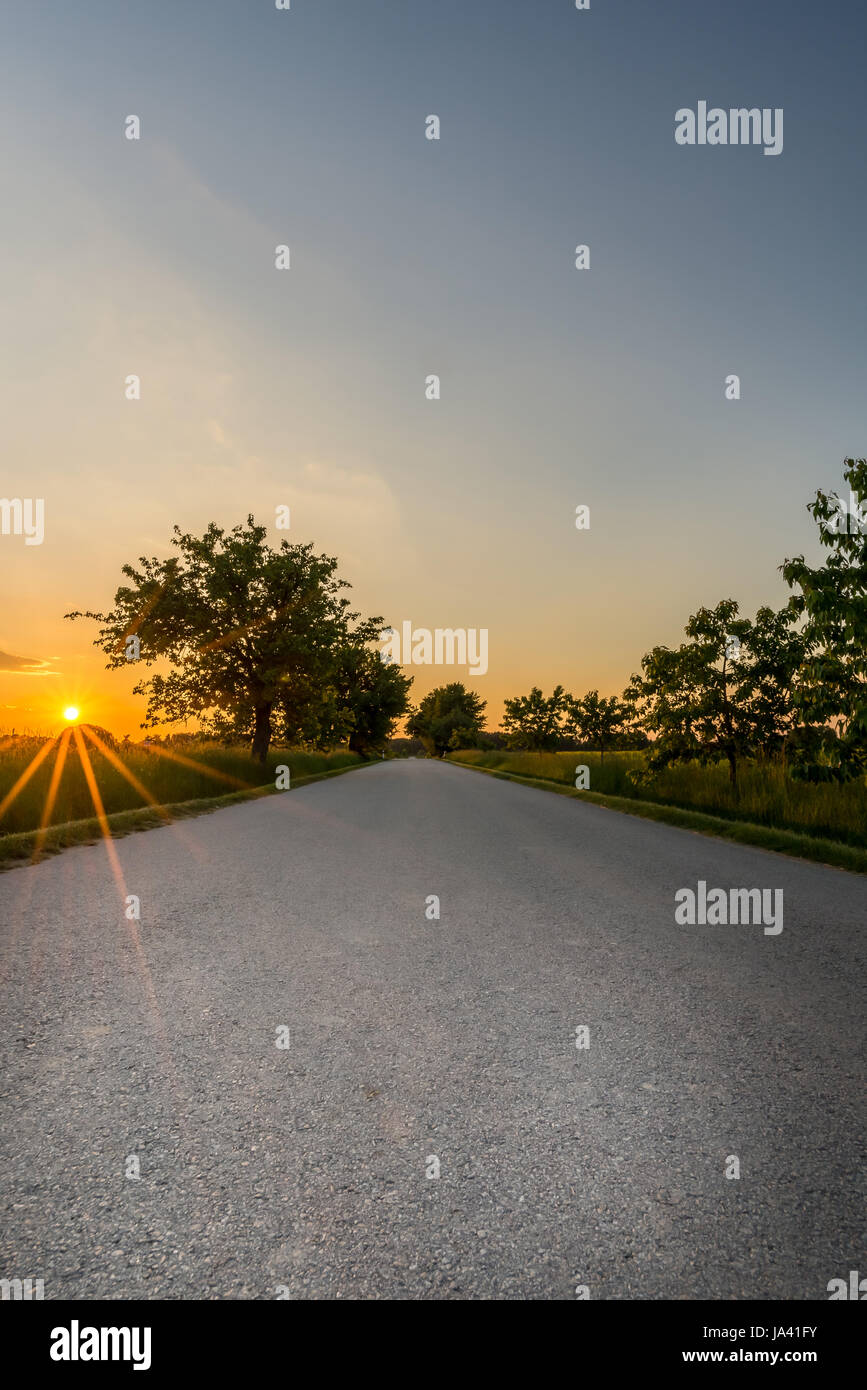 Vertical photo of country road with sunset in background. Grey road ...
