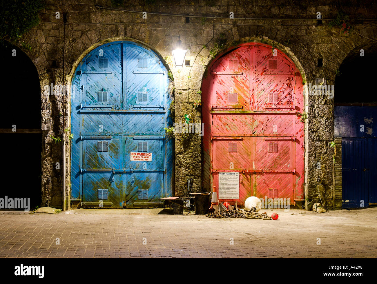 Night view of two archway doors illuminated by a light in Tenby Harbour ...