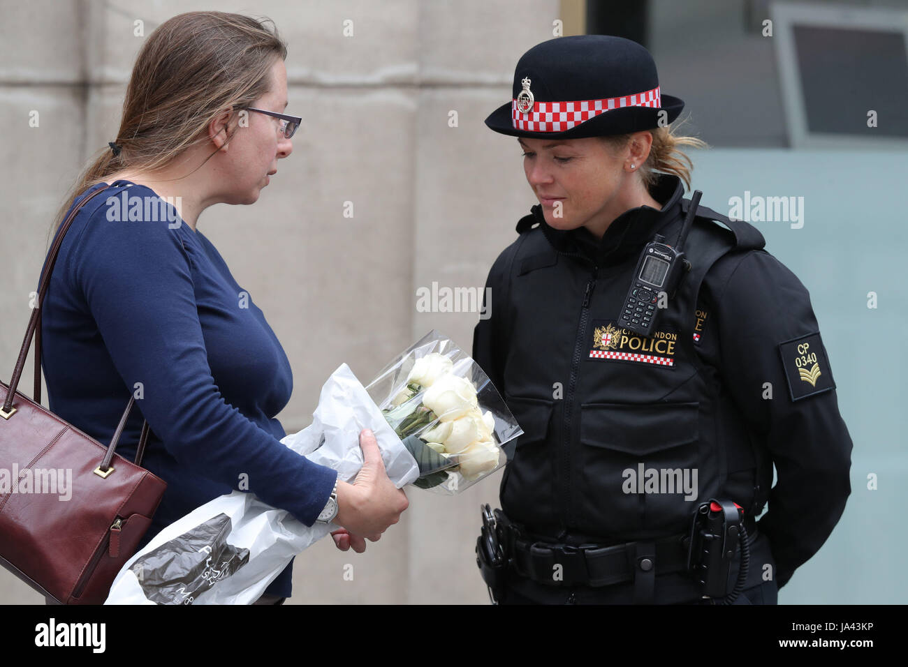 A member of the public speaks to a police officer as she brings flowers ...