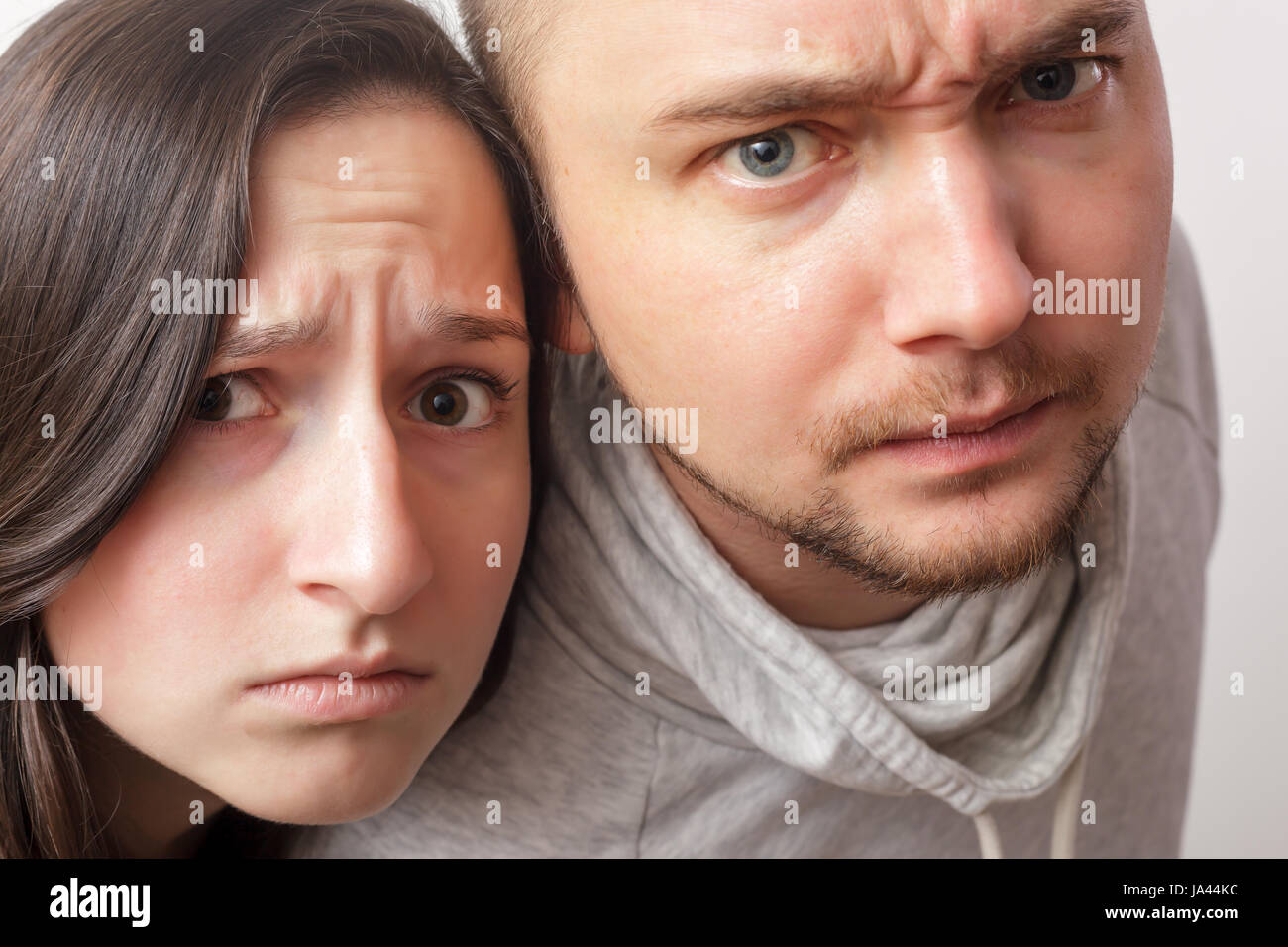 Young couple with dubious looks forward, wrinkling his face in ...