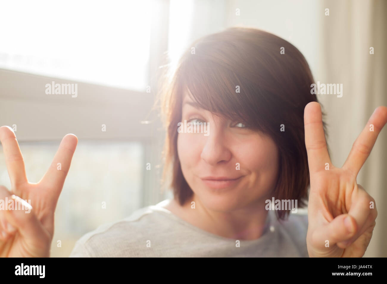 Caucasian girl shows victory gesture. Lens flare effect Stock Photo - Alamy