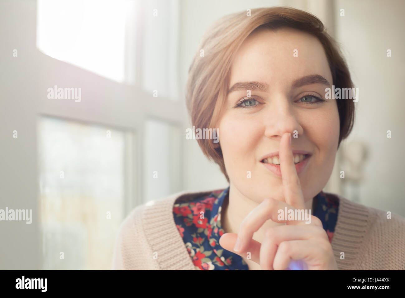 Girl holds a finger at lips. The sign of silence or secret Stock Photo ...