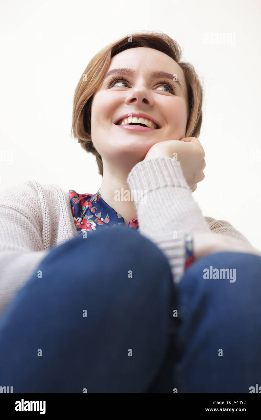 Caucasian girl sitting and looking to the side. Angle from the bottom ...