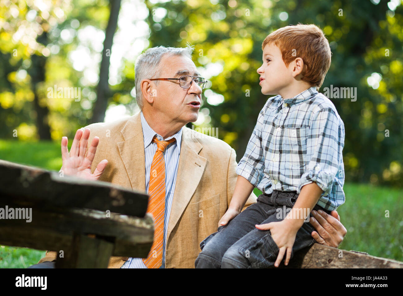Grandfather and grandson are sitting and talking in park Stock Photo ...