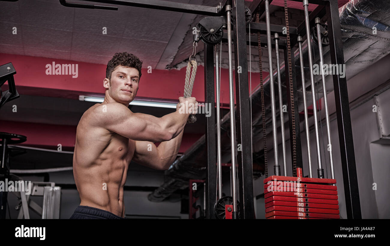 Young muscular guy exercising in the gym. Lifting heavy weights ...