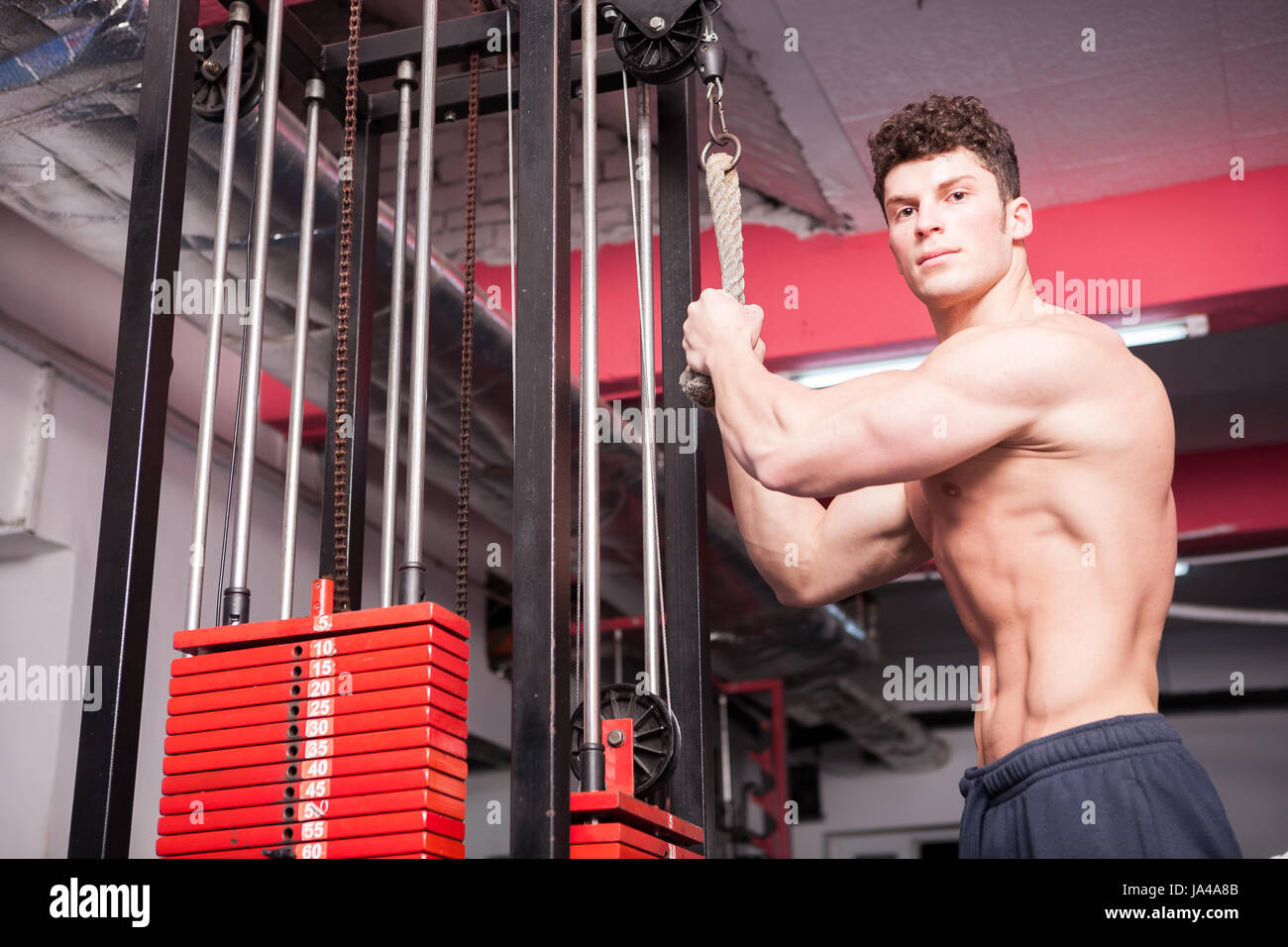 Young muscular guy exercising in the gym. Lifting heavy weights ...
