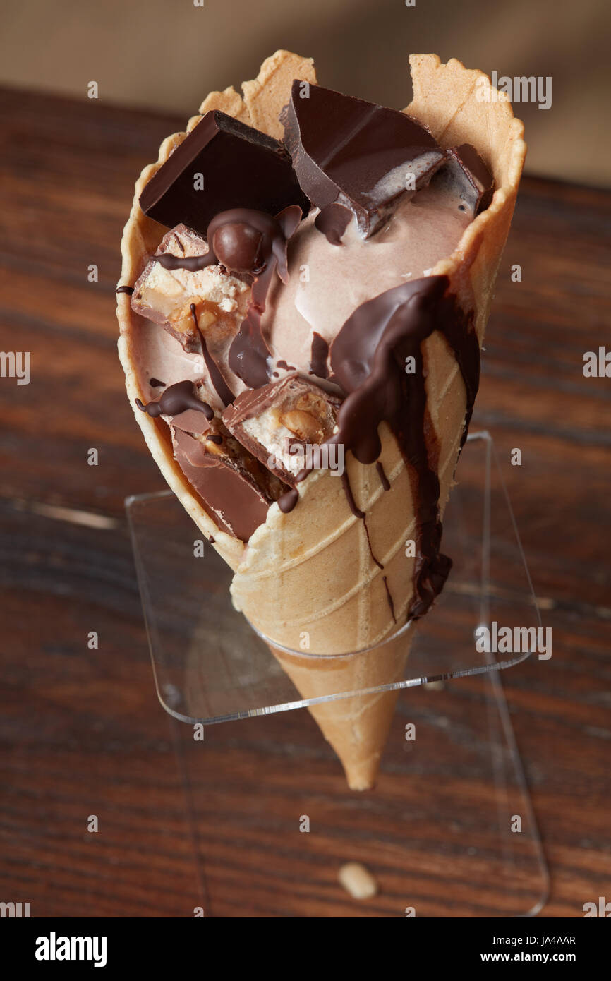 Waffle cone with melted ice cream chocolate syrup and pieces of ...