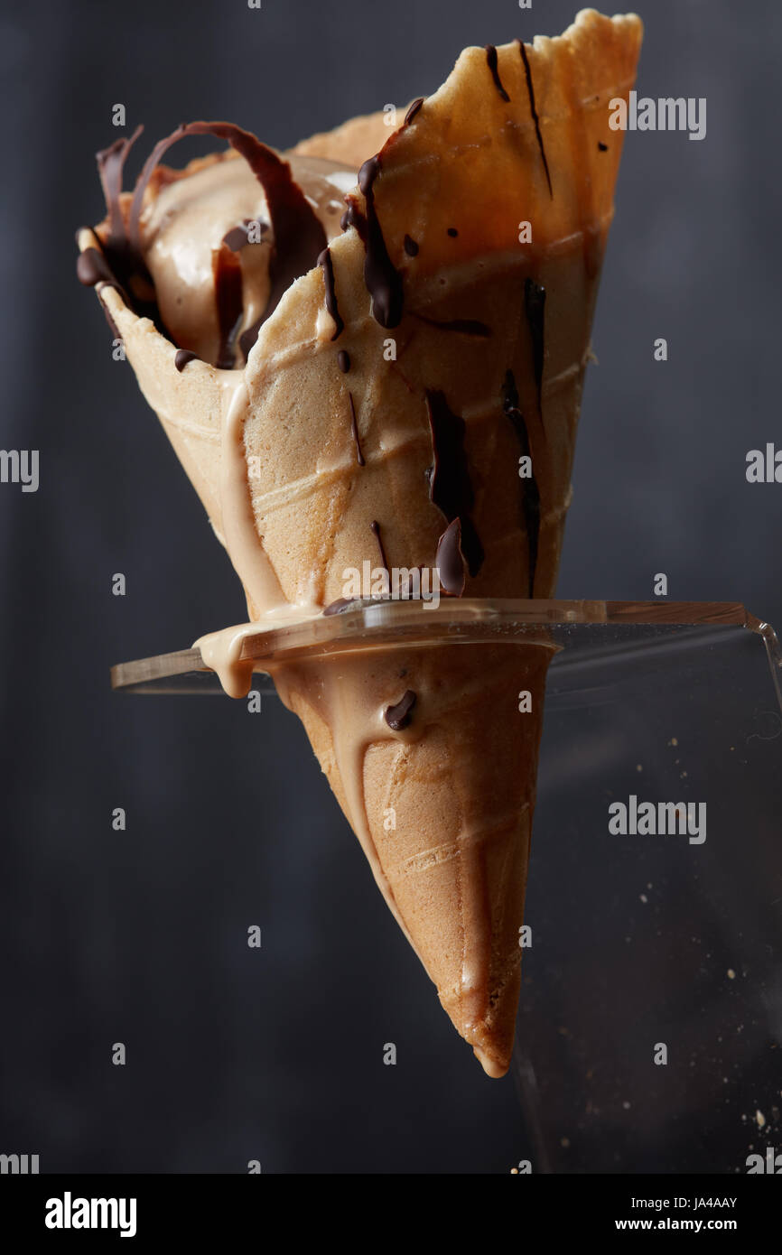 Close-up sinking ice cream in a waffle cone with chocolate syrup on a ...