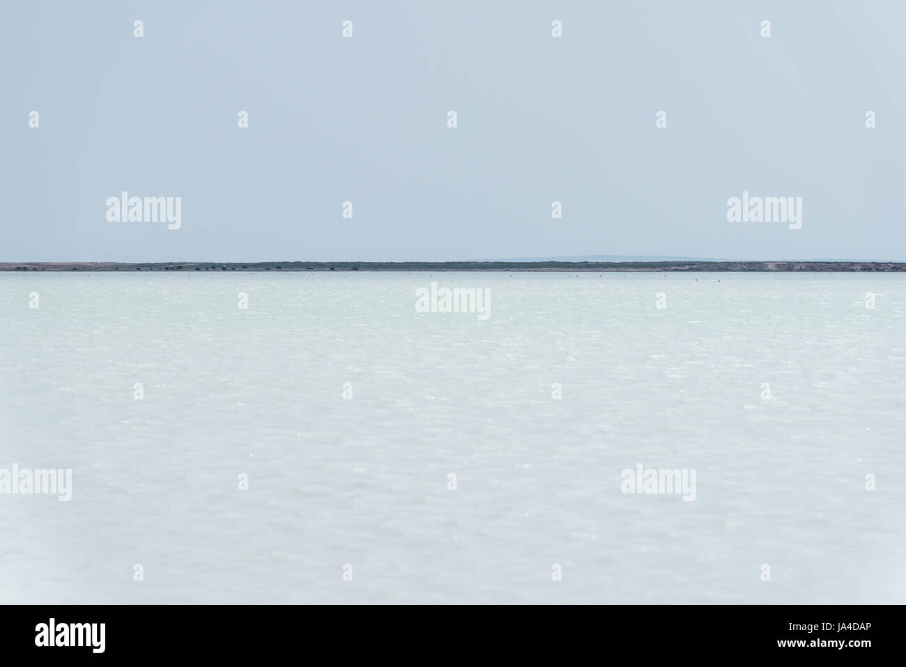 A minimalistic scene with a clear sky, blue water and a horizon line ...
