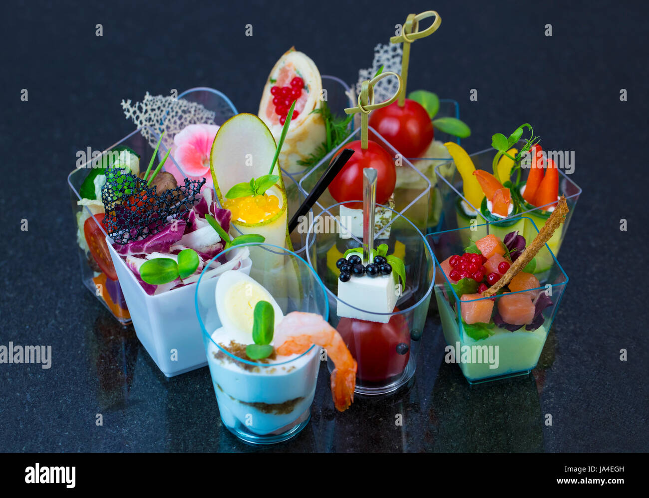 Mini desserts and meat canapes vegetable snacks in plastic cups canapes ...
