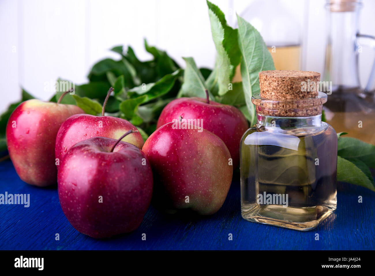 Apple cider vinegar. Three glass bottle on blue background. Red apples ...