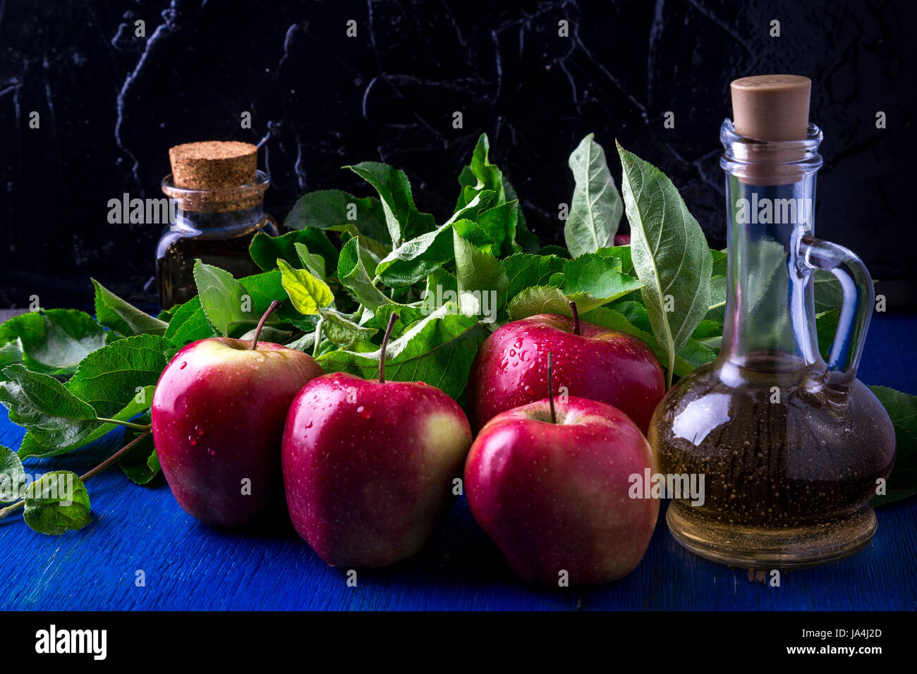 Apple cider vinegar. Three glass bottle on blue background. Red apples ...