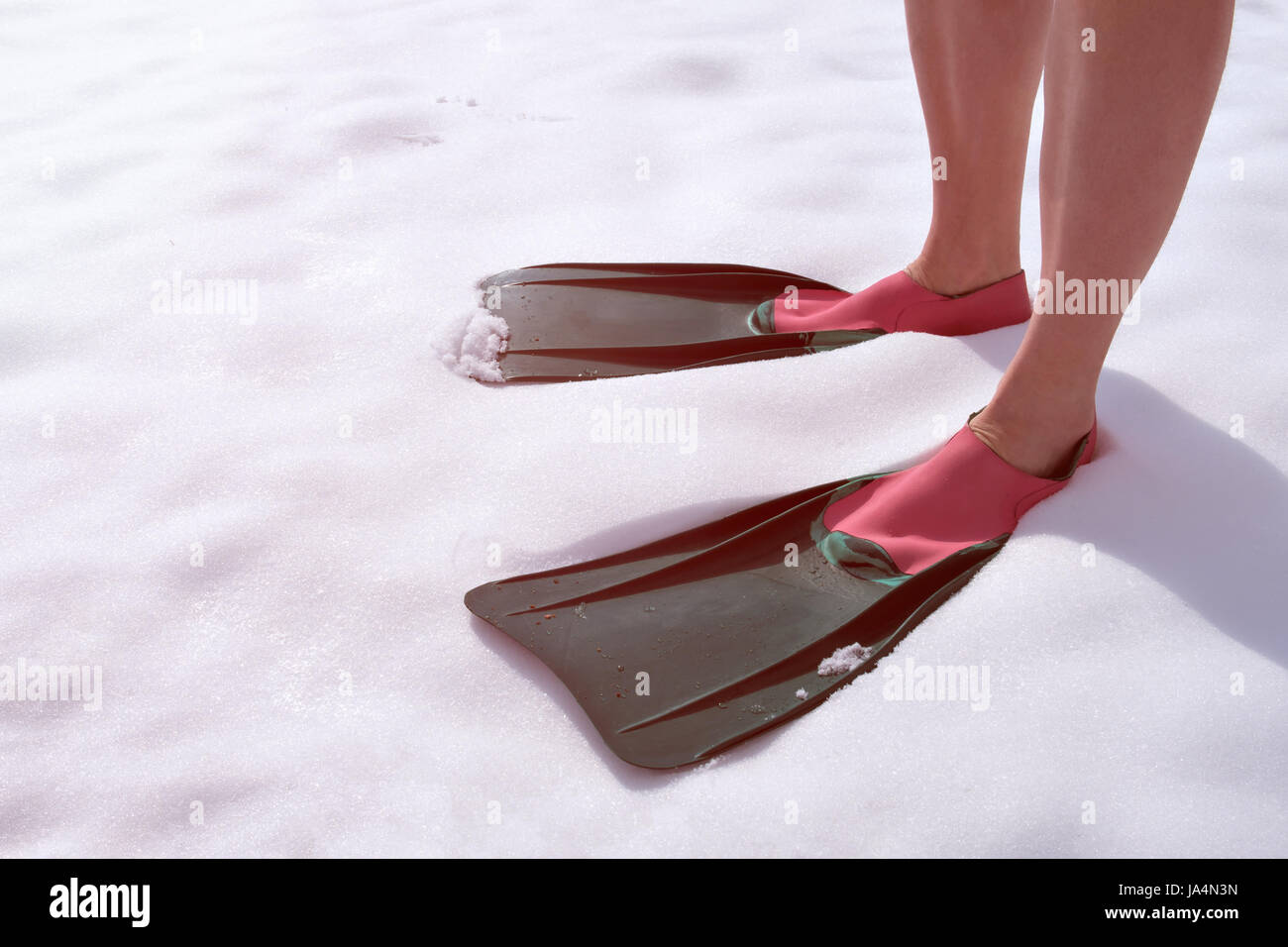 An athlete in swimming fins stands on the snow. To mix up the time or ...