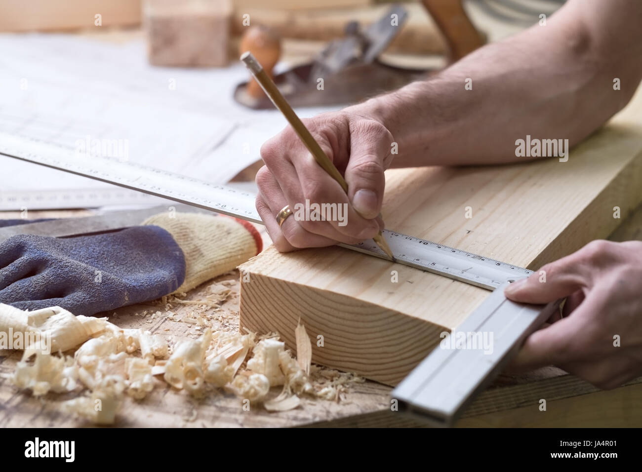 The carpenter makes marks with a pencil on a wooden strip. Preparing ...