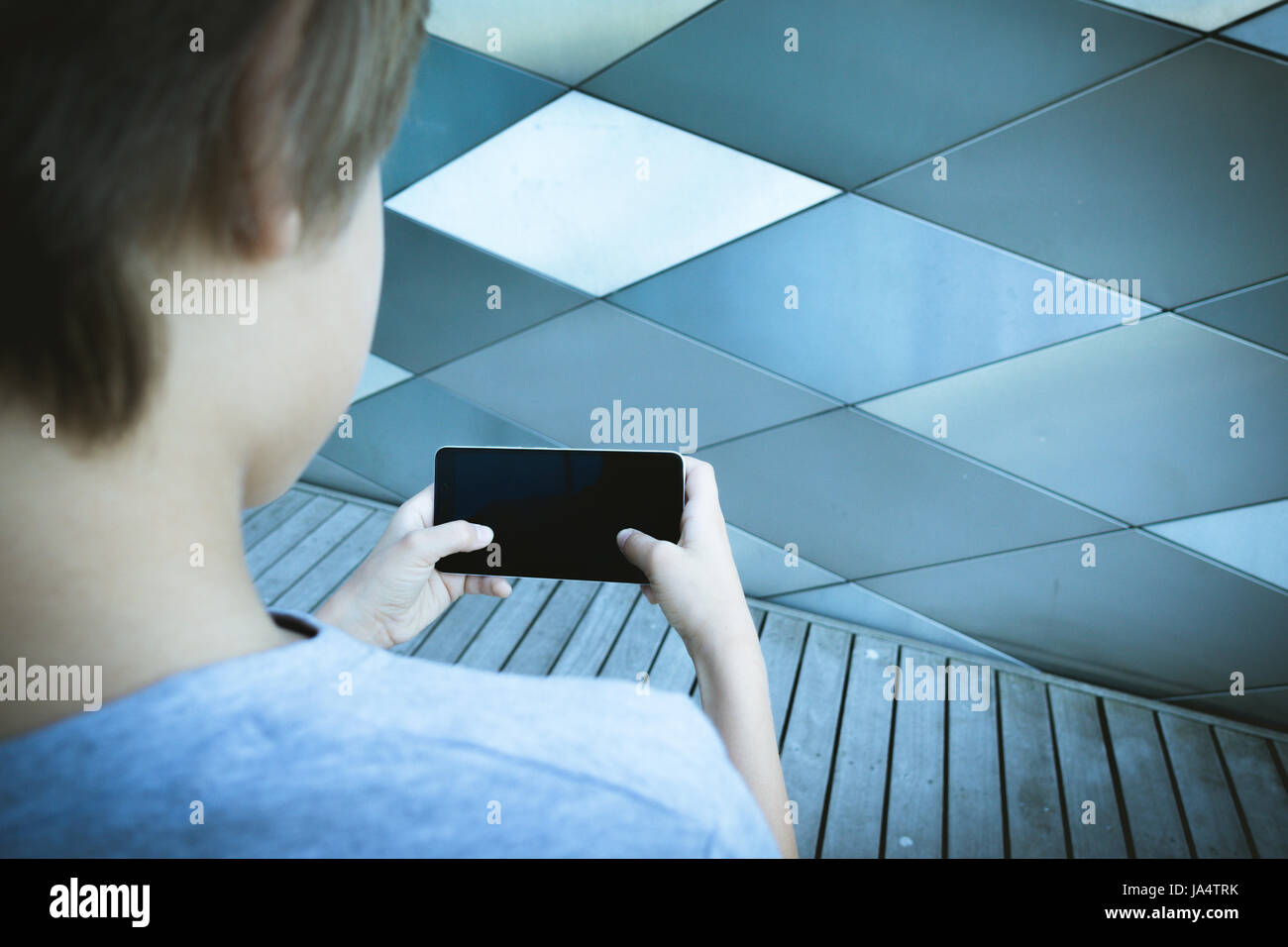 Boy using mobile phone. Back view Stock Photo - Alamy