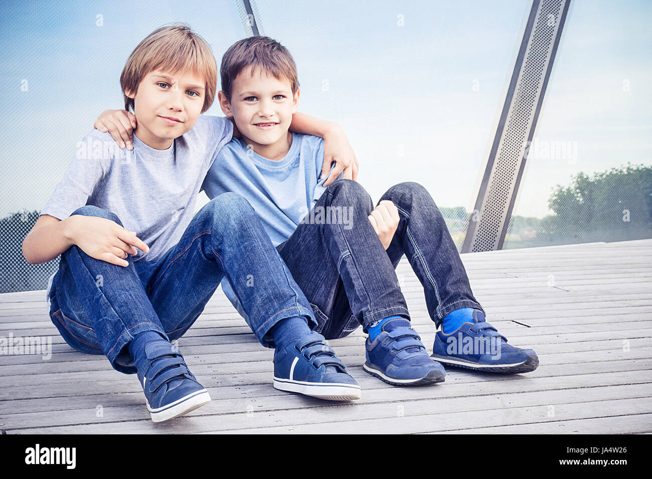 Two happy kids sitting together and embracing Stock Photo - Alamy