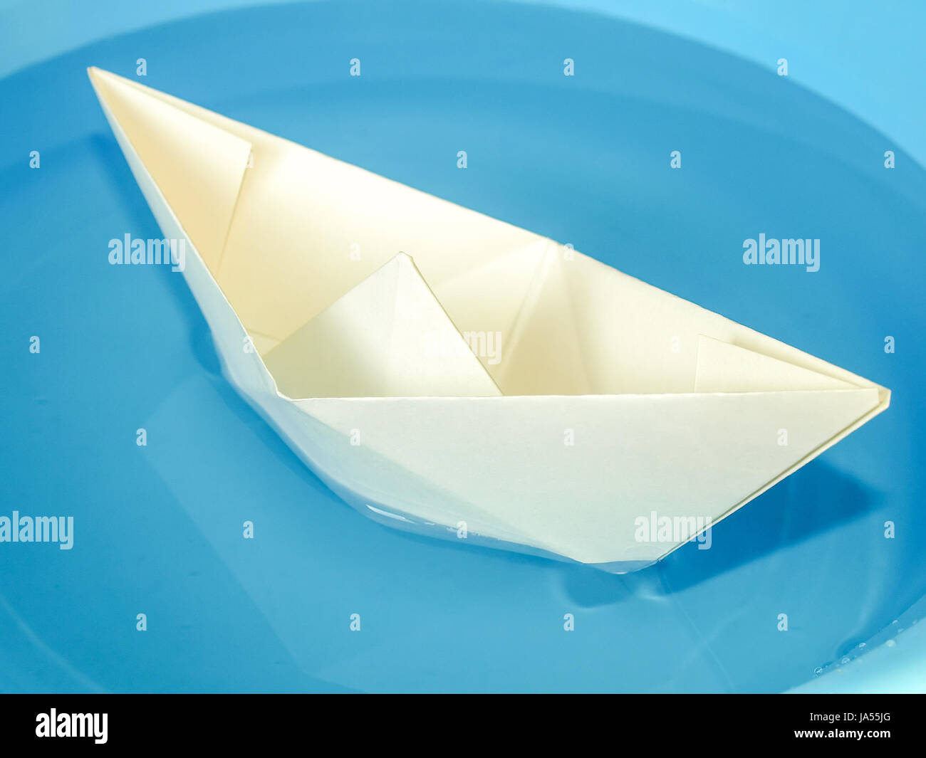 Toy paper boat over a blue water background Stock Photo - Alamy