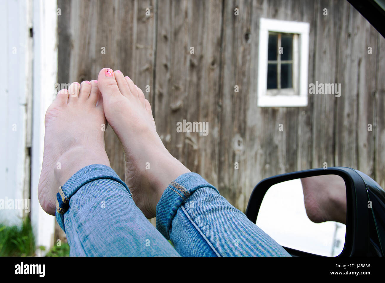 bare feet hanging out of car window with old barn background Stock ...