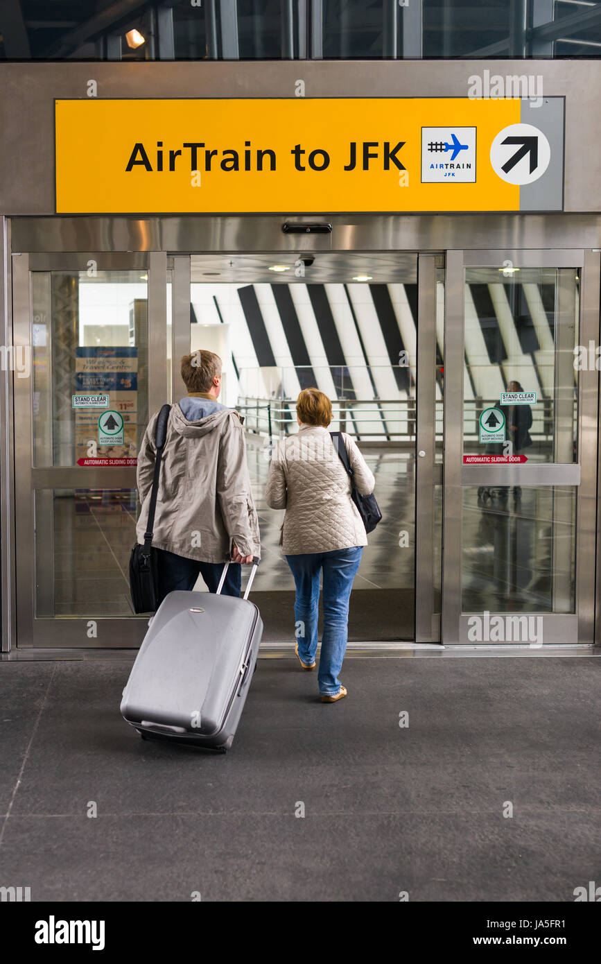 Two Female Passengers Walk With Suitcase Under a Sign For AirTrain to ...