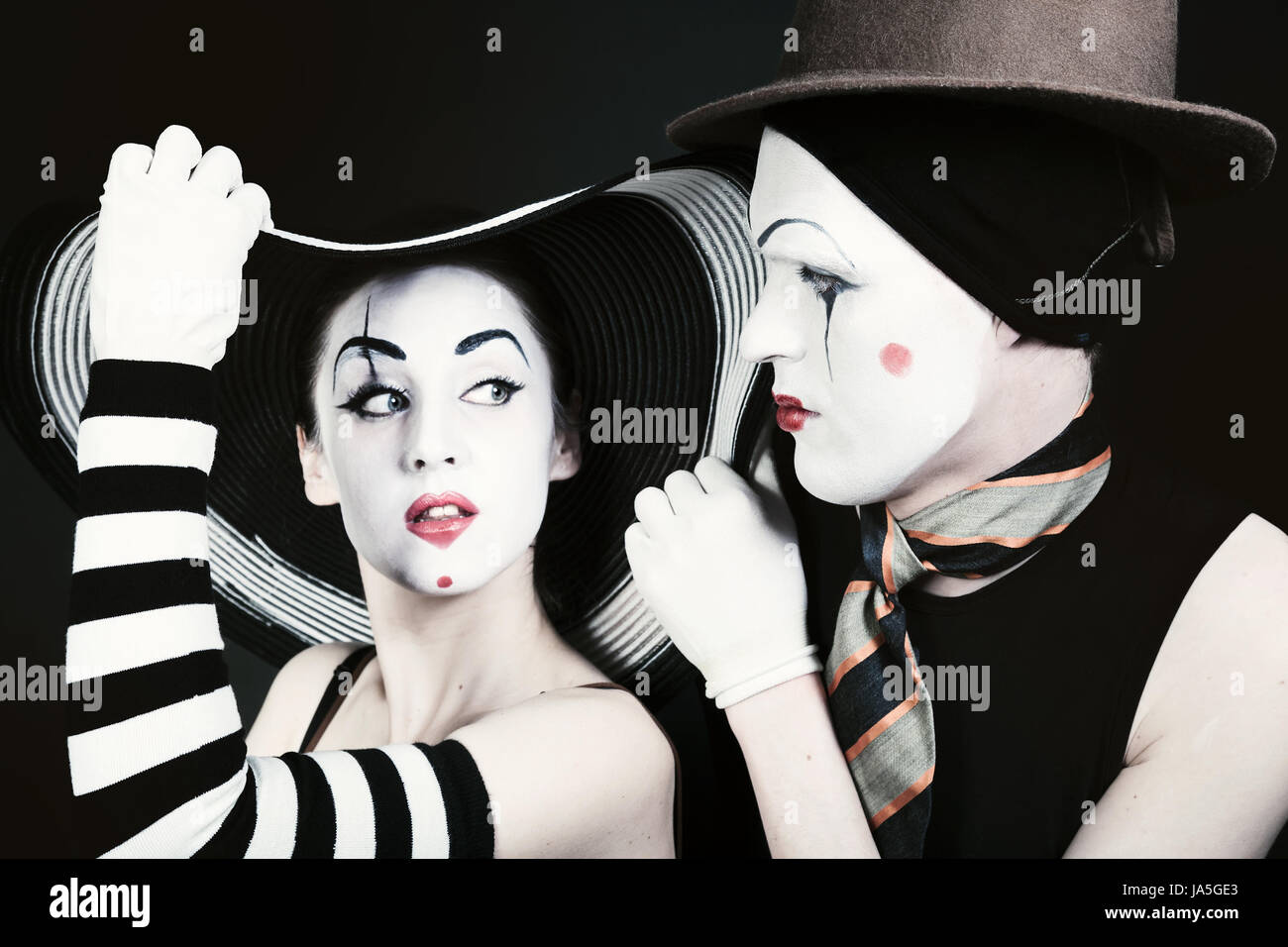 Portrait of two flirting mimes on a black background. Theatrical ...