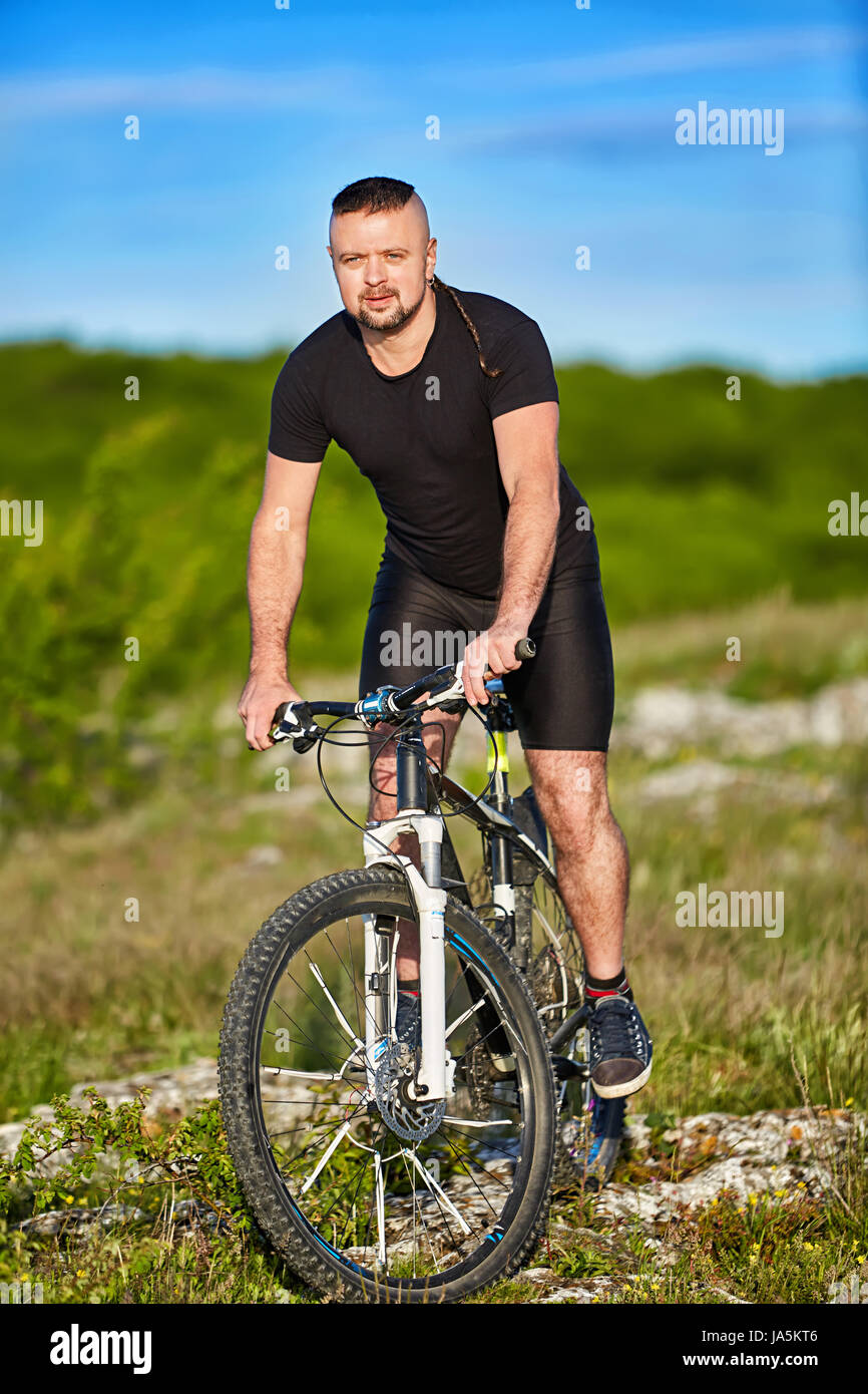 Portrait of athlete man riding mountain bike on the hill in summer ...