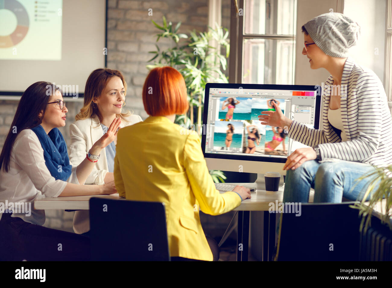 Young female graphics designers agreeing about design of front page of ...