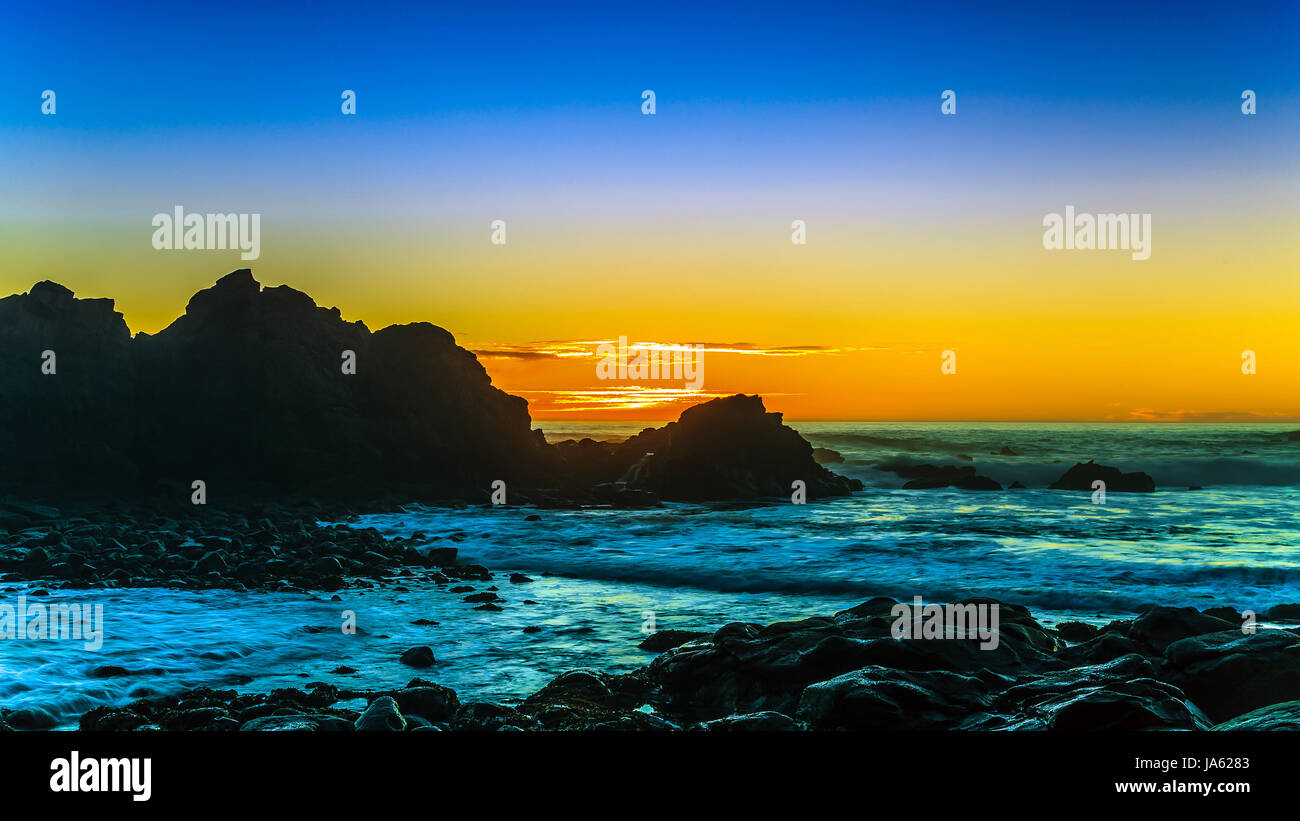 Rocky yellow sunset at shore Stock Photo - Alamy