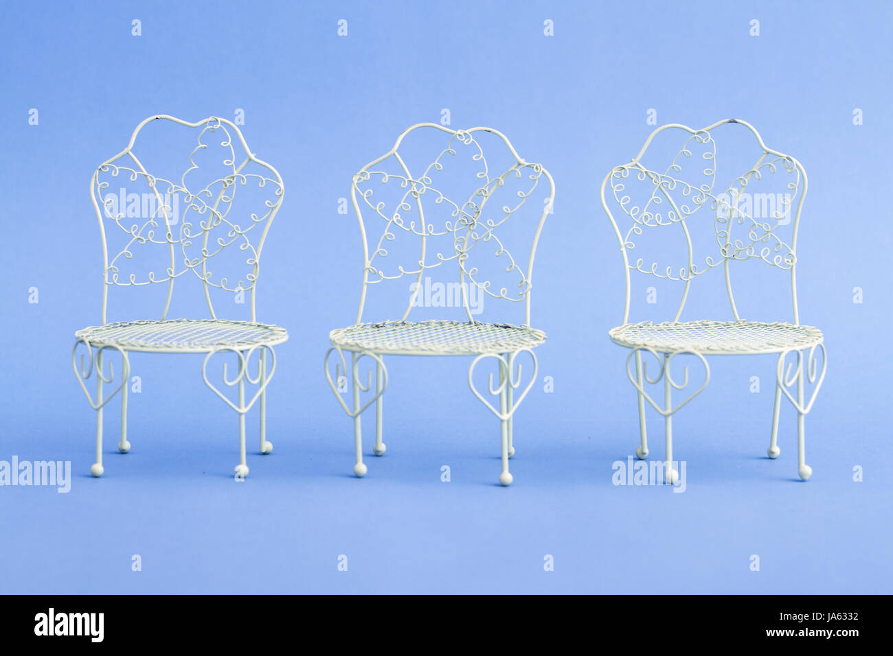 Pink and white decorative mini wrought iron chairs on purple background ...