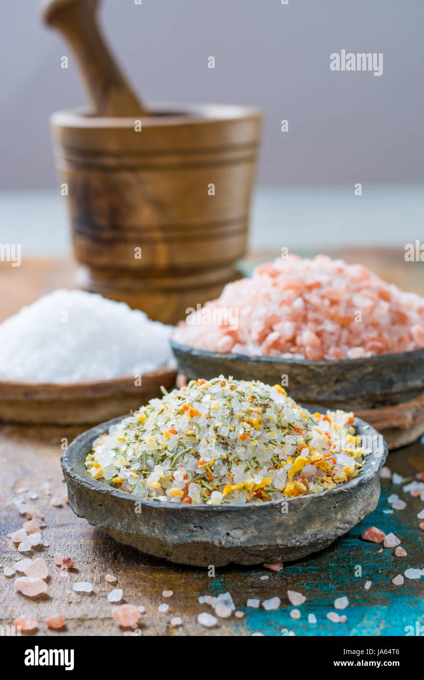 Different types of natural salt in stone bowls on wooden surface. White ...