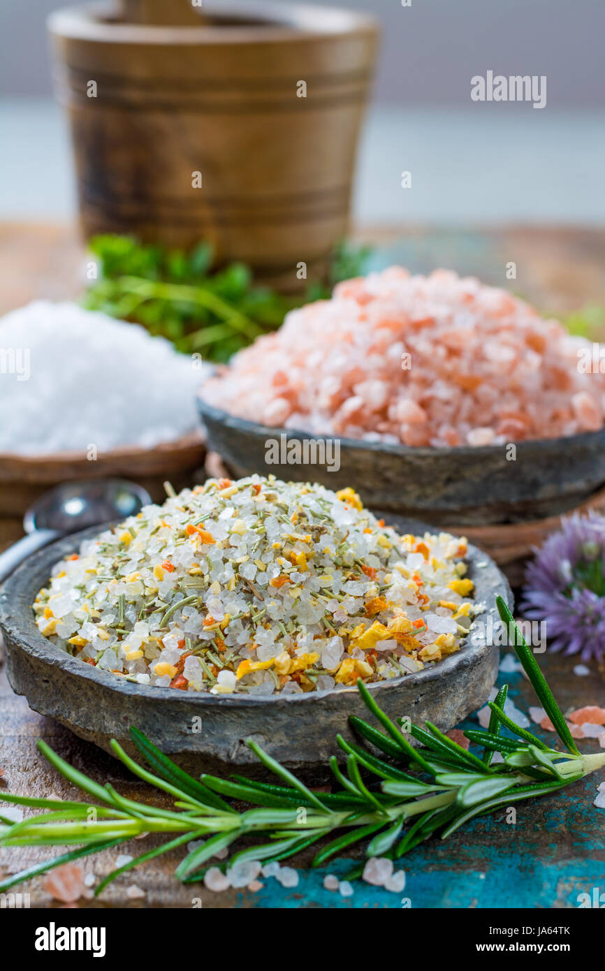 Different types of natural salt in stone bowls on wooden surface. White ...