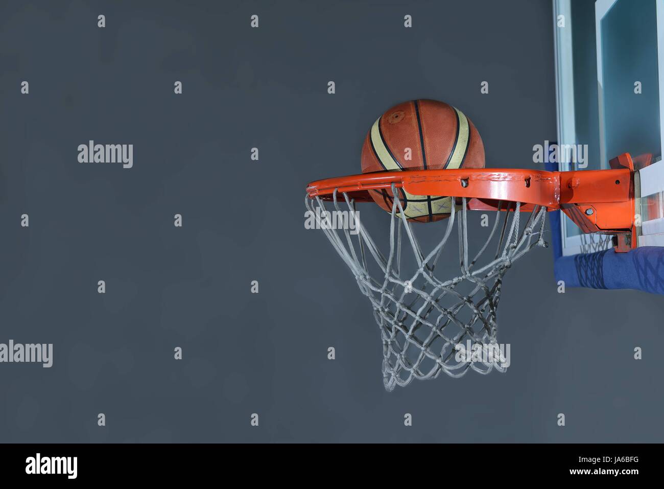 Basketball ball, board and net on grey background in gym indoor Stock ...