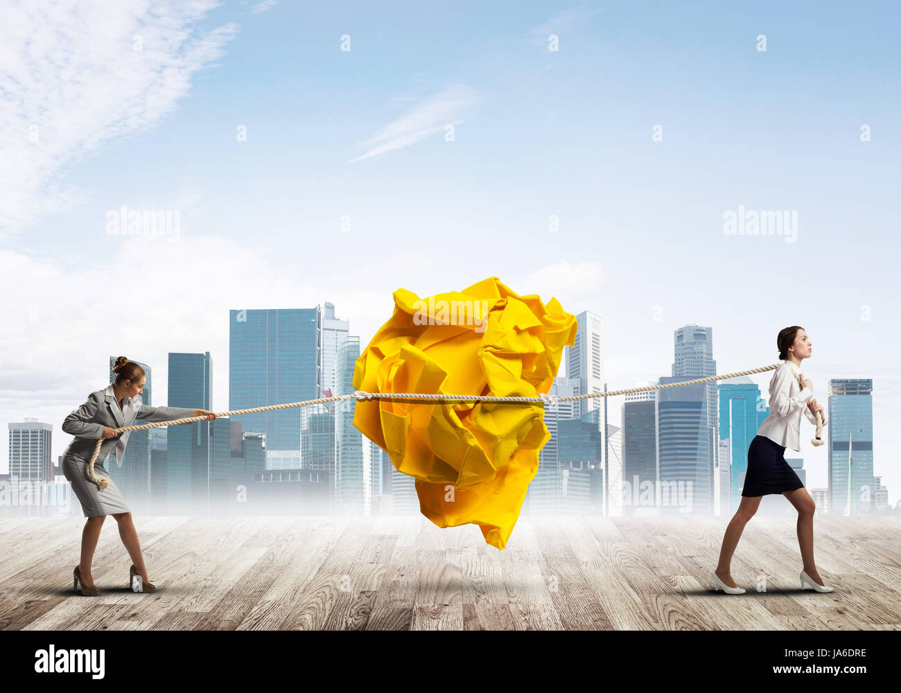 Two women pulling with effort big crumpled ball of paper as creativity ...