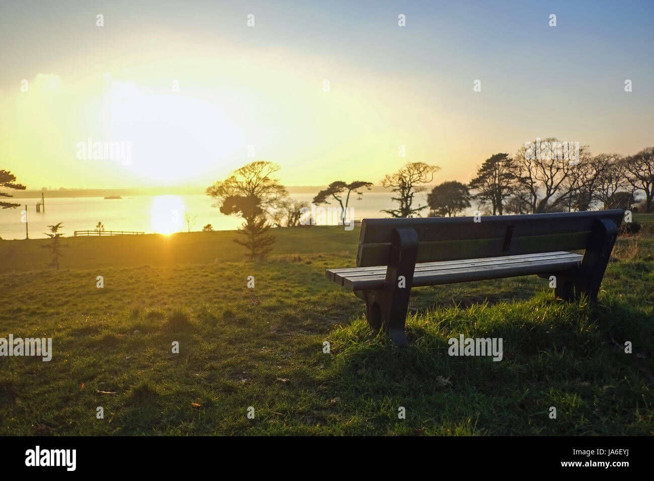 Park bench facing sunset over sea in Royal Victoria park Hampshire ...