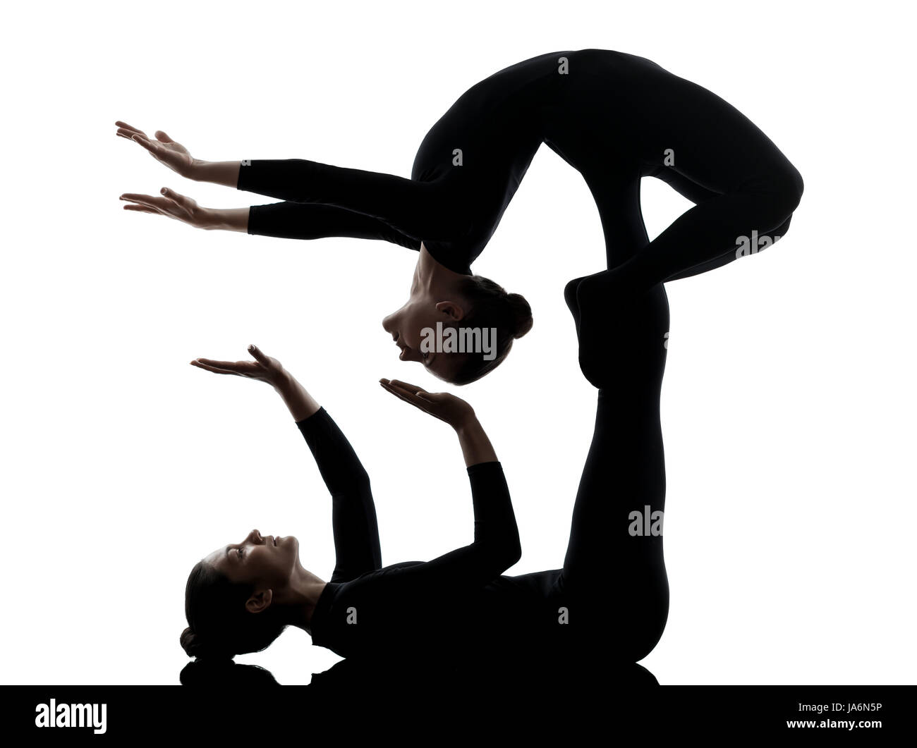 two women contortionist practicing gymnastic yoga in silhouette on ...
