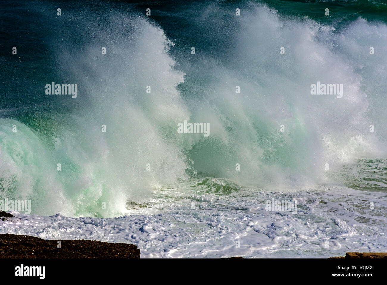 Wave crashing against rocks during storm Stock Photo - Alamy