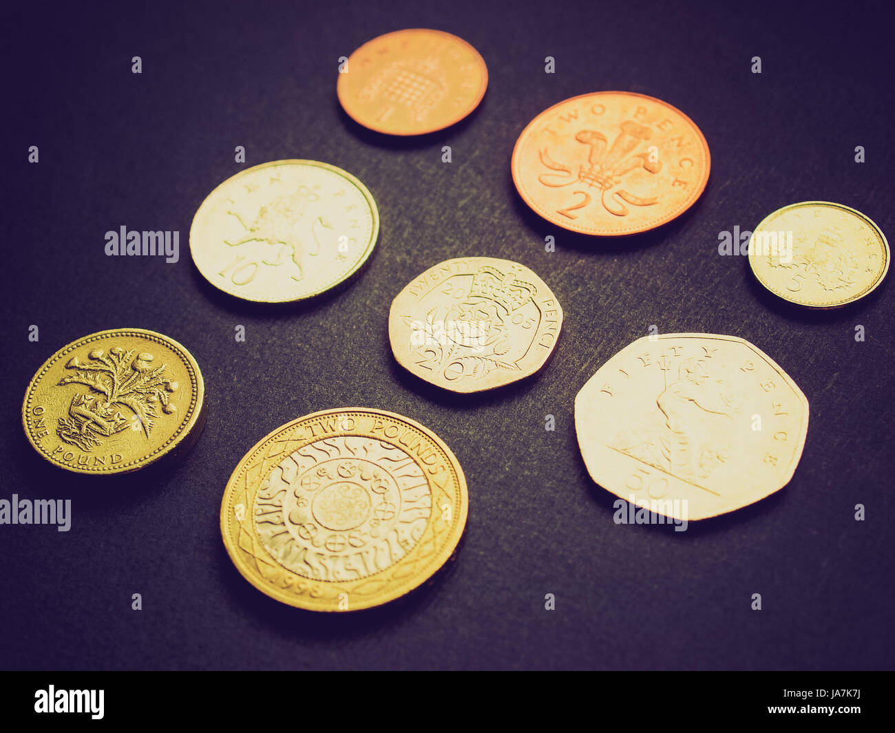 Vintage looking British Pounds coins (UK currency) over a dark ...