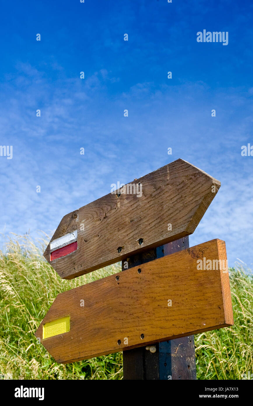 Two wooden sing with up and down directions in grass field with blue ...