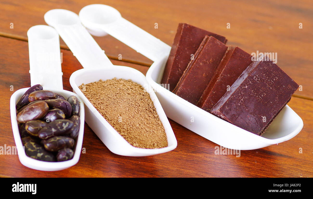Dark dry cocoa bean, pieces of chocolate and powdered cocoa inside of a ...
