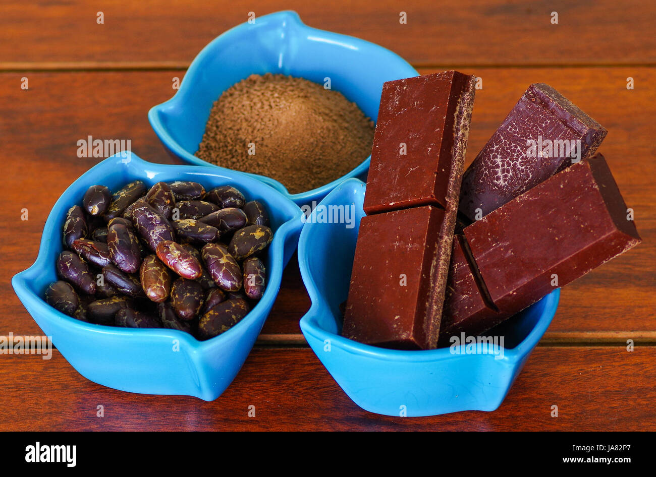 Close up of a dark dry cocoa bean, pieces of chocolate and powdered ...